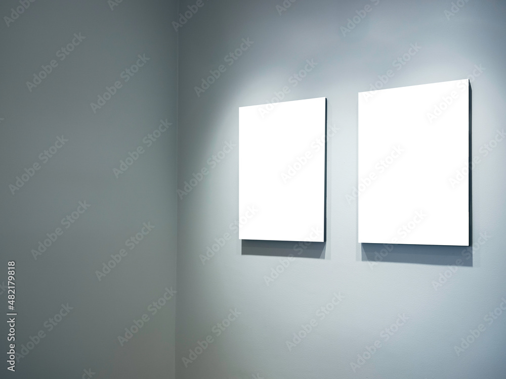 Two mockup vertical rectangle painting frames hanging on white wall ...