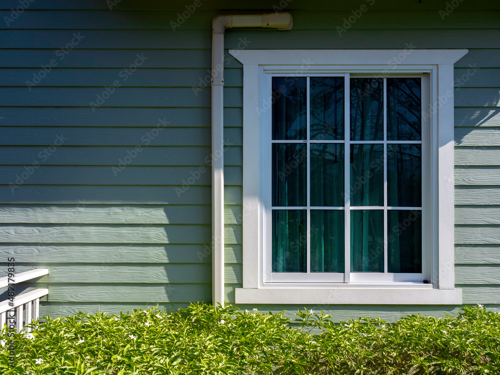 A white house window with glass, green curtain decoration on the small ...