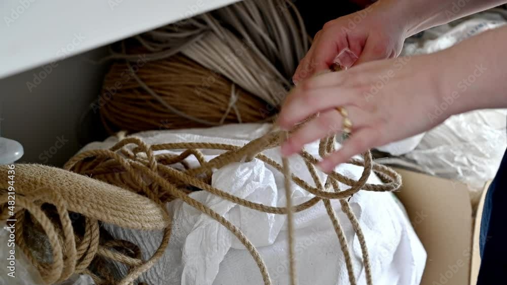 Video „Female hands pulling on a jute rope and undoing knots in the ...