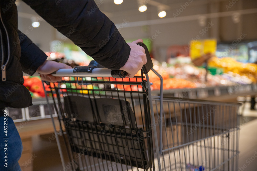 jeune homme qui fait ses courses dans un supermarché, il pousse son ...