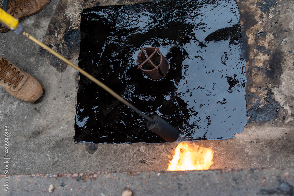 Downpipe repair. Heating bituminous mastic with gas burner during ...