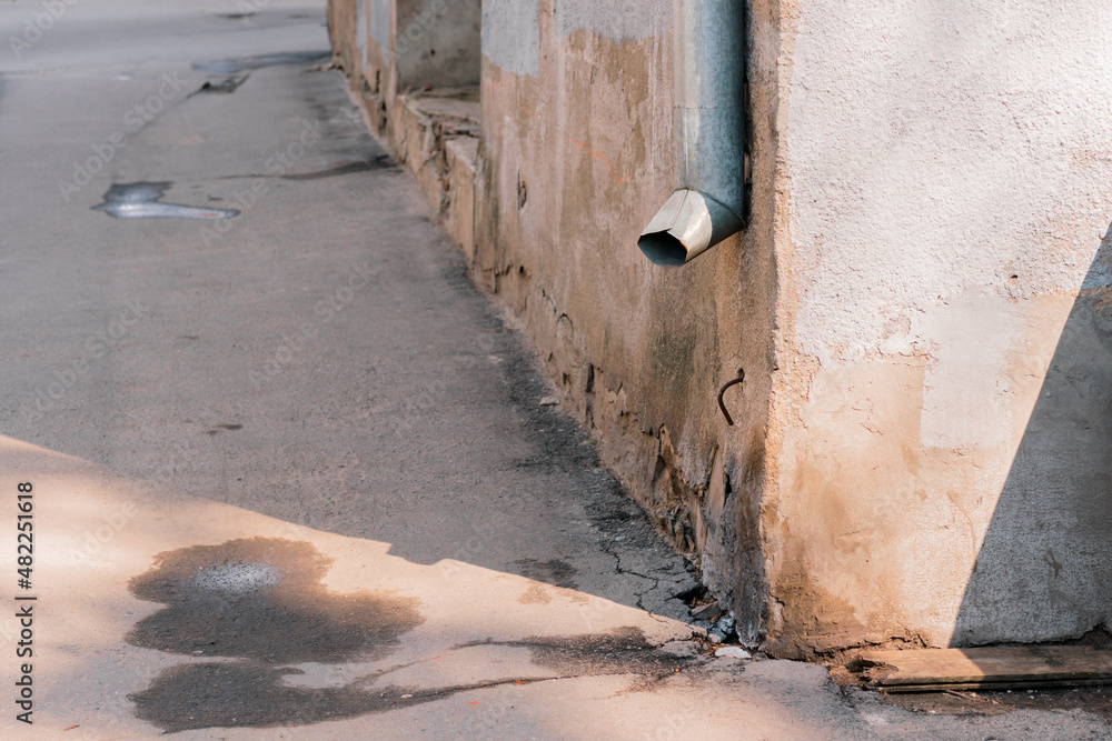 Grey stainless pipe rain system on the damage concrete plaster facade ...
