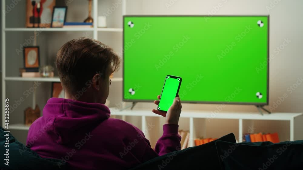 Man watching television in living room. Young guy sitting on sofa ...