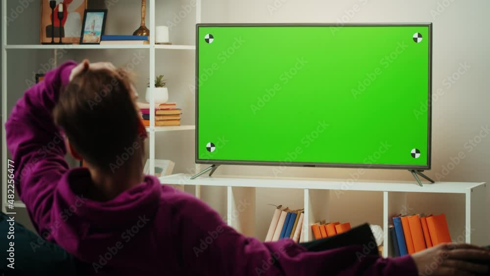Man watching television in living room. Young guy sitting on sofa ...
