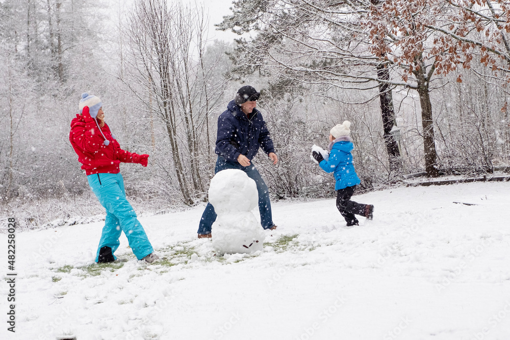 Snowball game. Caucasian family man, woman and child 5 years old make a ...