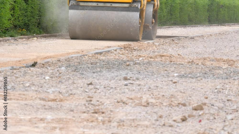 Footage of a road roller leveling a soil substructure for a new walkway ...