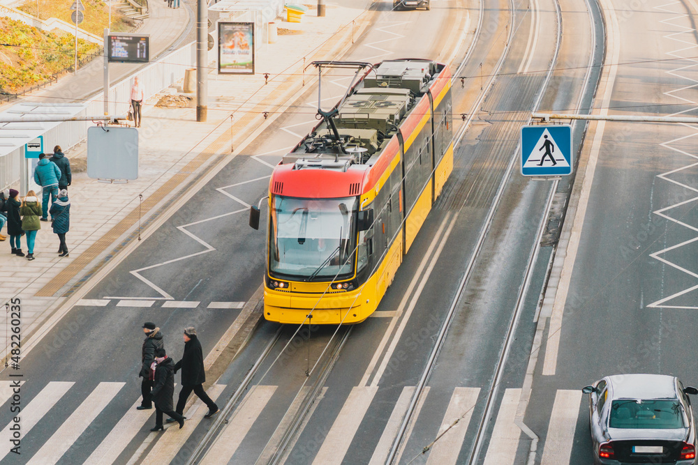 Group of people crossing the street in front of tramway moving forward ...