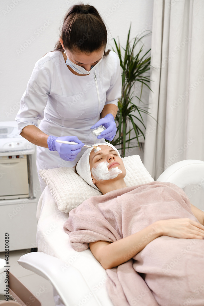 Cosmetologist apply skin mask with brush, care and treatment procedure ...