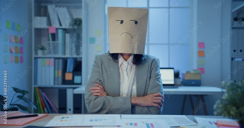 Young Asian businesswoman sit on desk wear draw sad mask paper craft ...