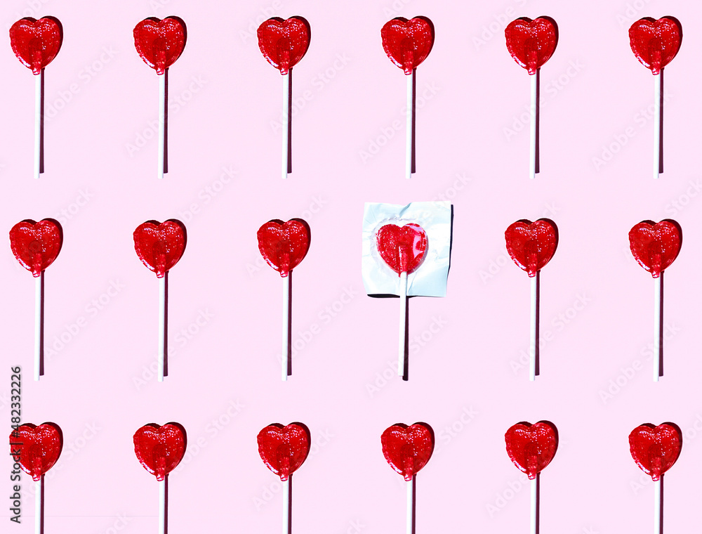Pattern of heart shaped lollipops flat laid against pink background ...