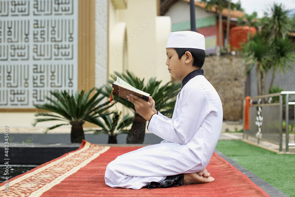 Side view An Islamic boarding school student reading the Quran in the ...