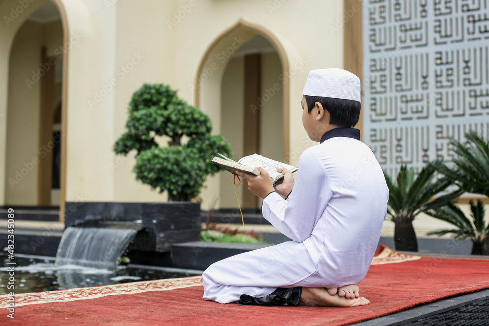 An Islamic boarding school student kneeling while reading the Quran in ...