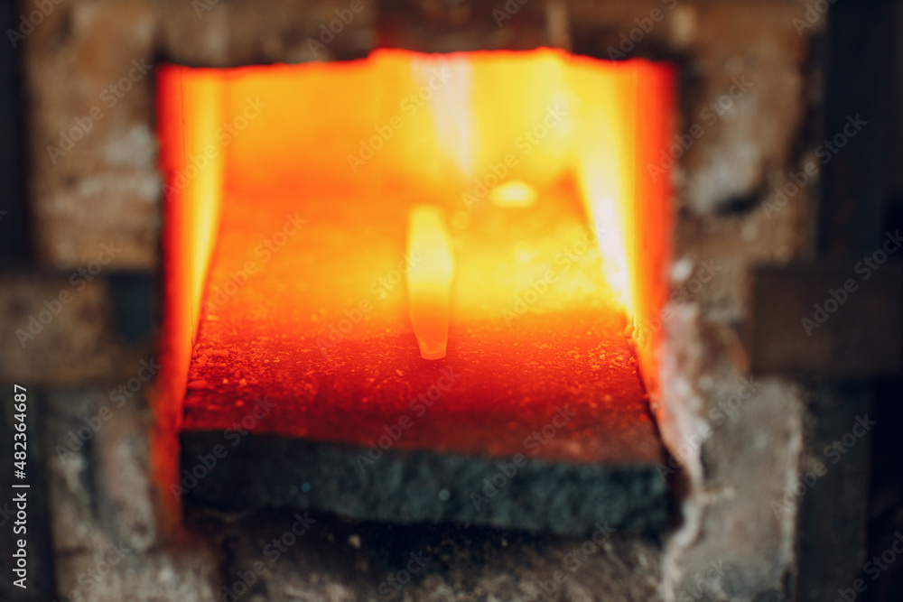 Blacksmith forge oven with hot flame. Smith heating iron piece of steel ...