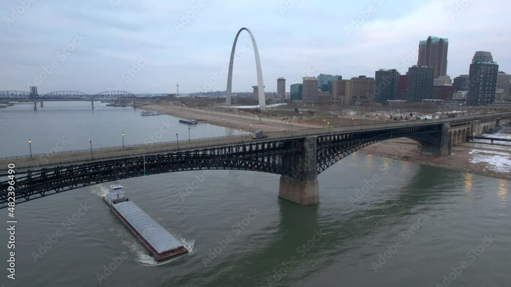Barge on Mississippi River goes under Eads Bridge. Gateway Arch visible ...