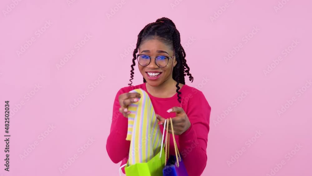 African-American girl in pink clothes looks in paper laminated bags ...