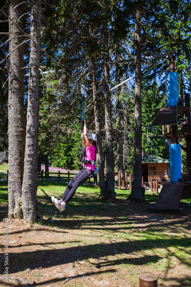Child using safety equipment at adventure amusement park. Young girl ...