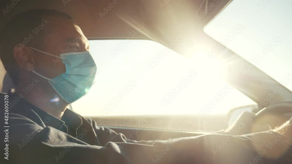 worker driver wearing medical mask drives a car during the coronavirus ...