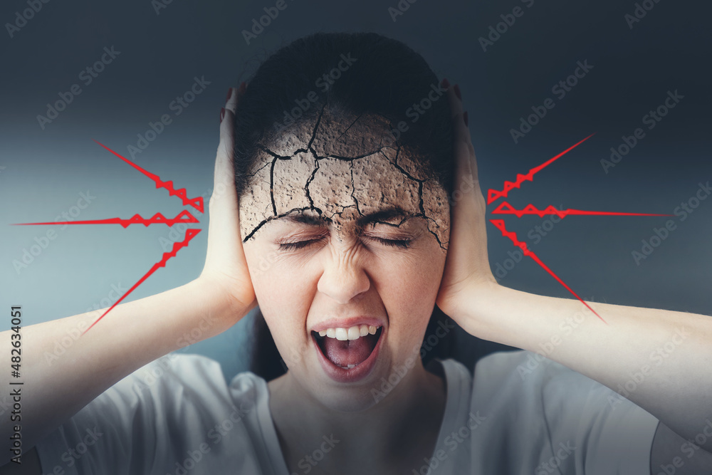 Portrait of a screaming young Caucasian woman covering her ears with ...