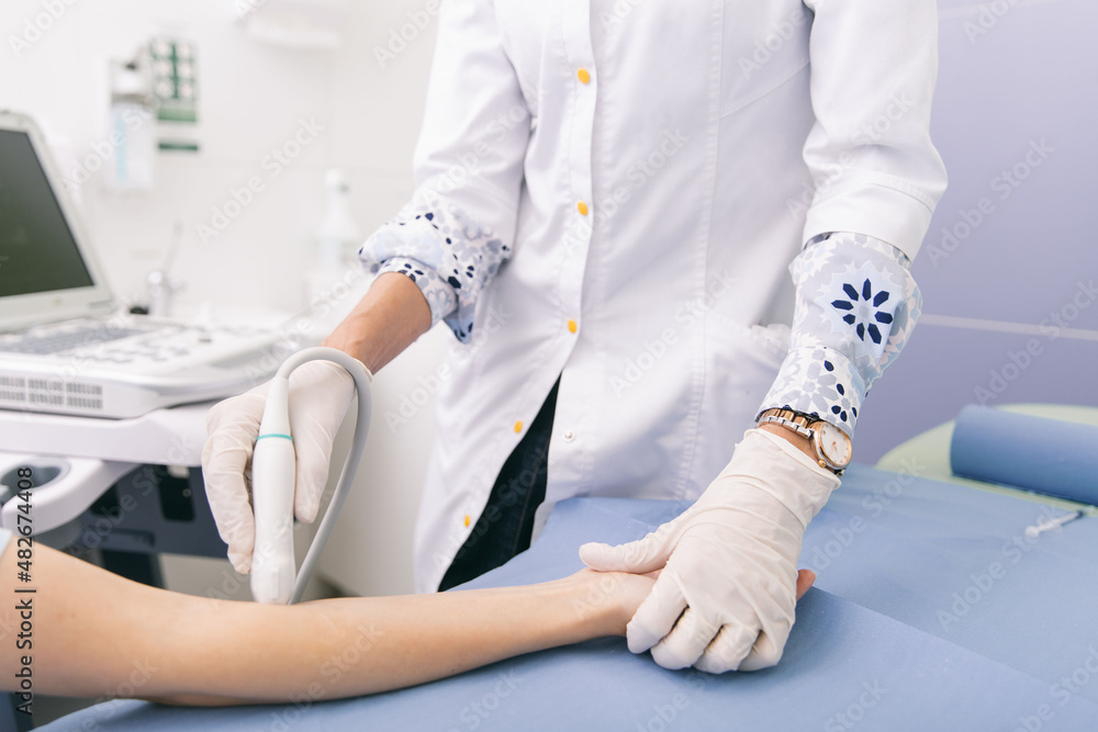 Doctor doing the ultrasound on the hand close up. Doctor demonstrates ...