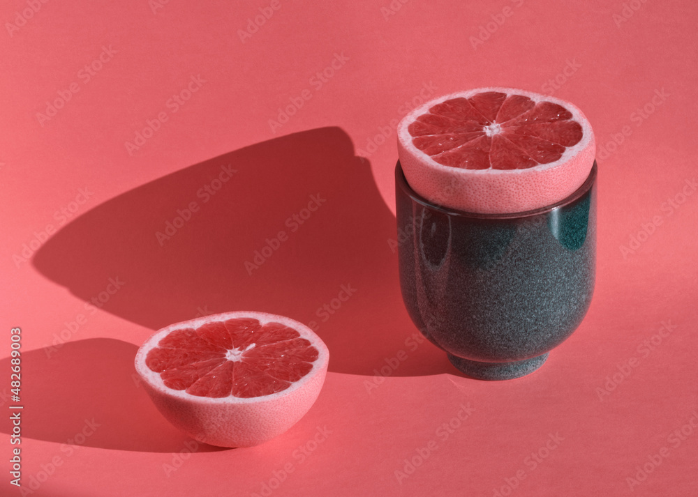 Ripe pink sliced grapefruit on blue ceramic on soft pink background ...