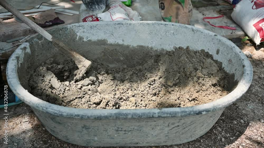 Worker using hoe mixing cement, sand and water in bucket Stock Video ...