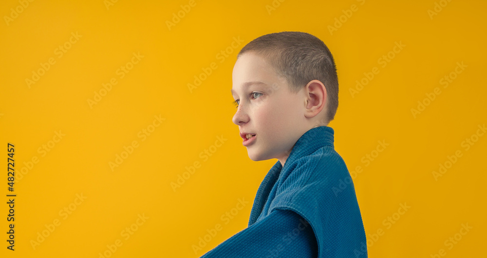 boy in blue sportswear stands sideways and looks to the side, yellow ...