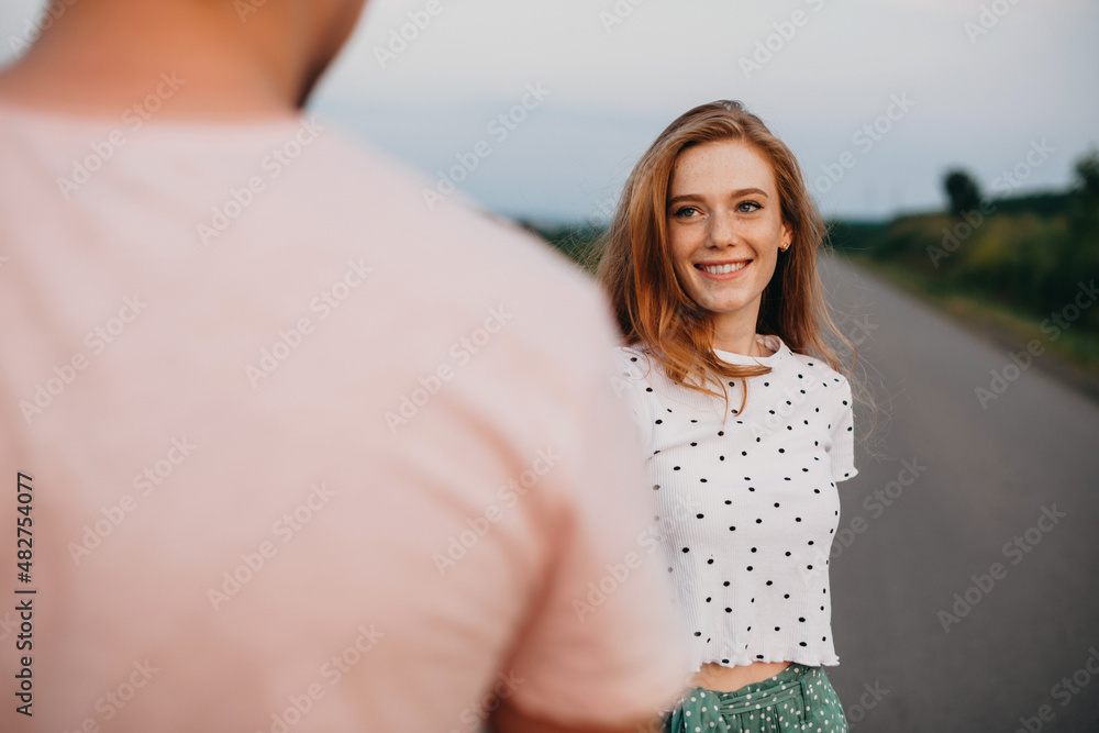 Portrait of a freckled woman smiling and looking into the eyes of her boyfriend holding her hand ...