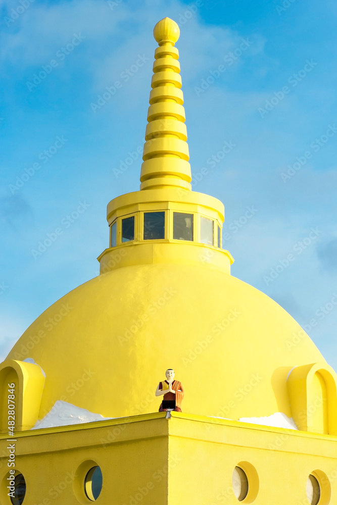 Tibetan bright yellow temple stupa with prayer monk figurine at top ...