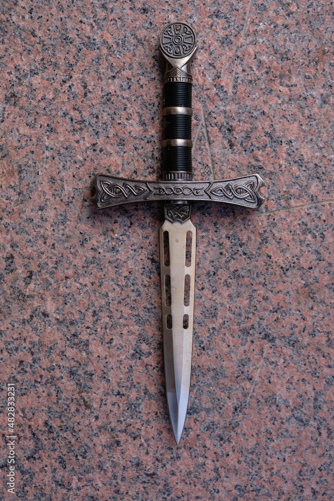 Decorative dagger knife on a granite background. Vertical image. Stock ...