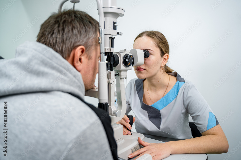 Doctor and patient in ophthalmology clinic. Male patient checking ...