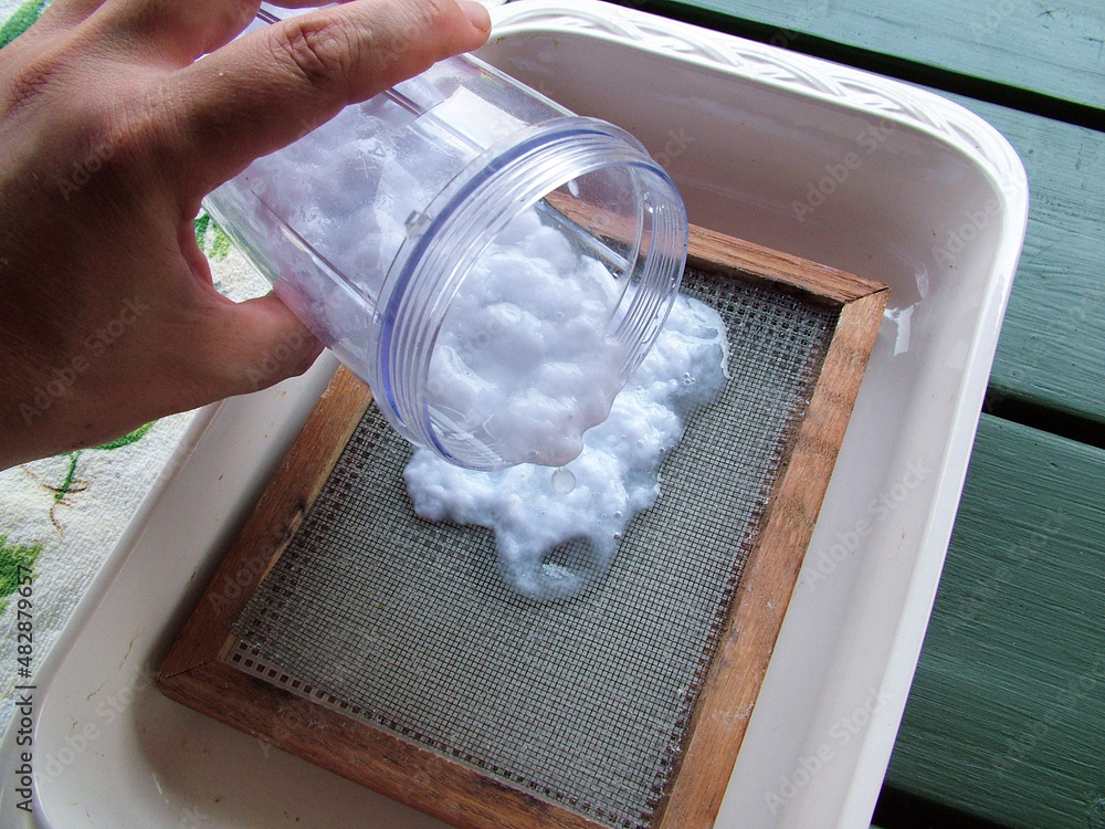 Pouring white paper pulp into a mold to make handmade paper Stock Photo ...