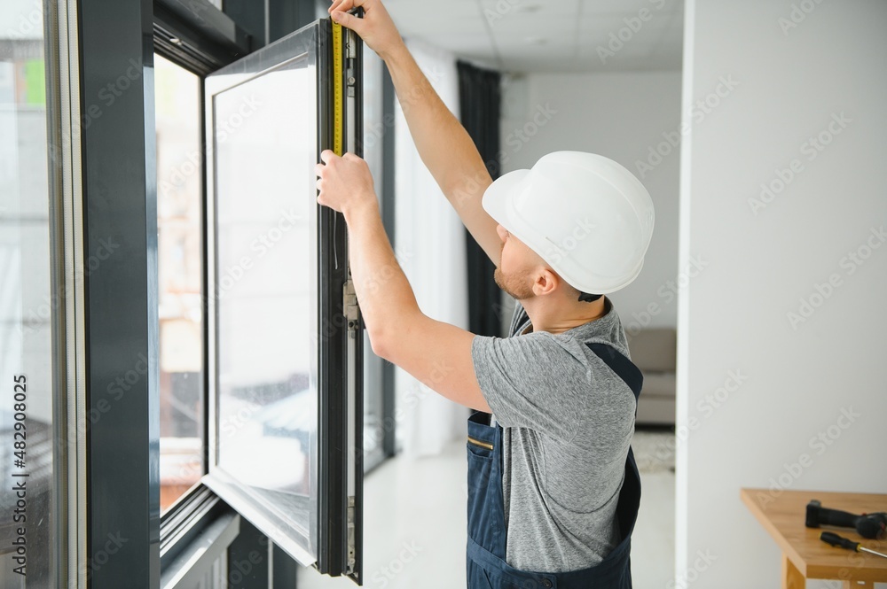 handsome young man installing bay window in new house construction site ...