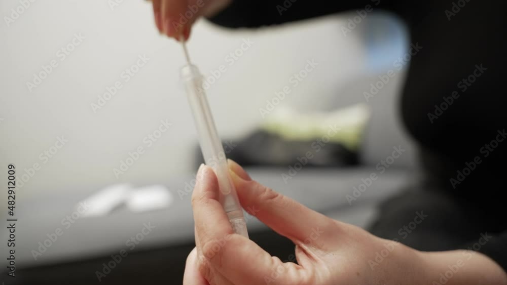 Female hand swirl nasal swab inside tube in Antigen Covid-19 home rapid ...