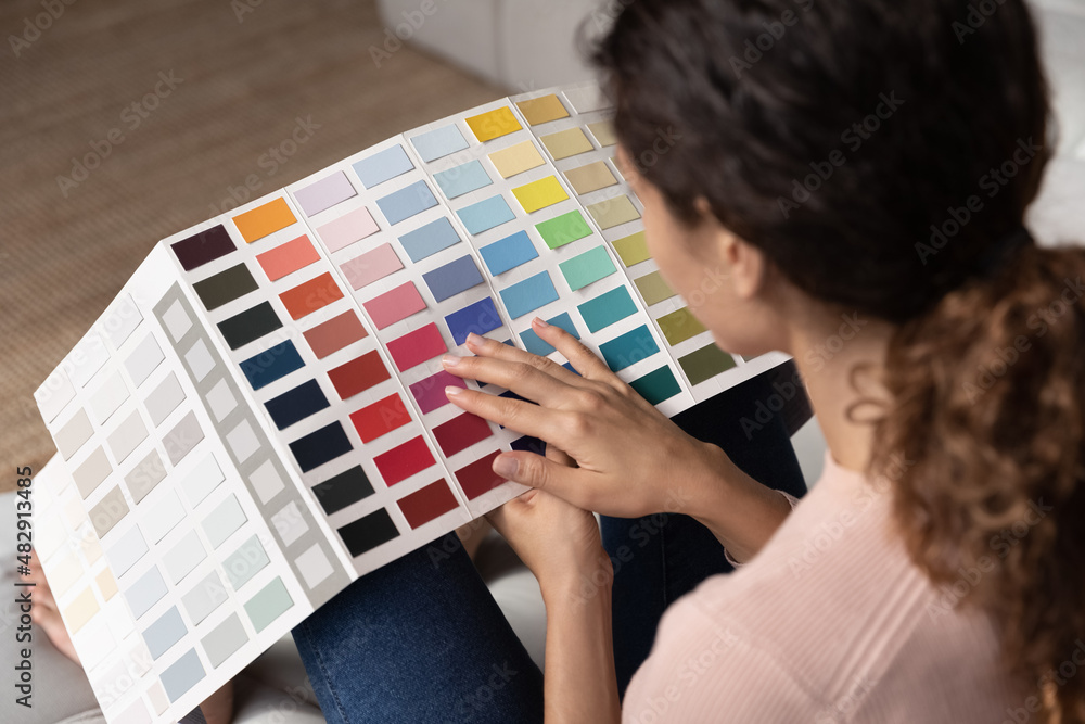 Rear close up view over female shoulder holds swatches looks at pantone ...