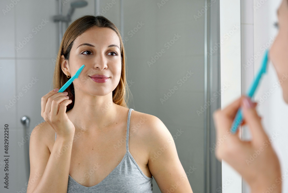Beautiful young woman shaving her face by razor at home. Pretty woman ...