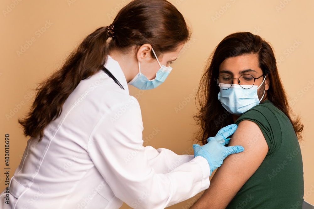 Foto de Woman doctor making intramuscular injection for arab guy at ...