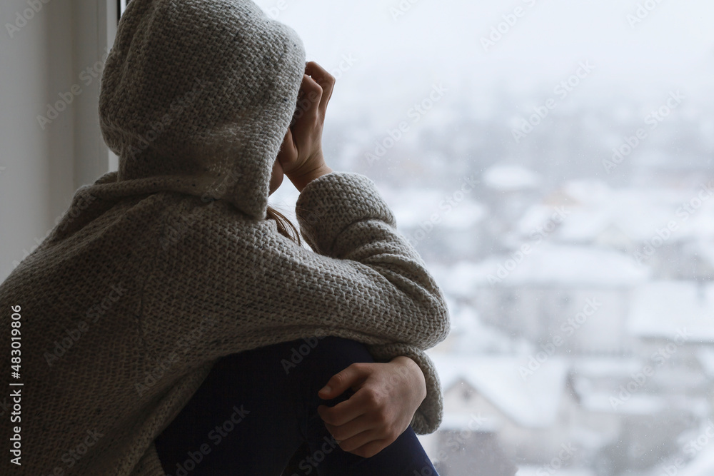Depressed Upset sad teen girl looks out the window back to the camera ...