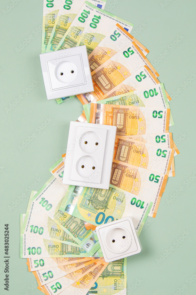 Electric sockets with Euro banknotes on light green background ...