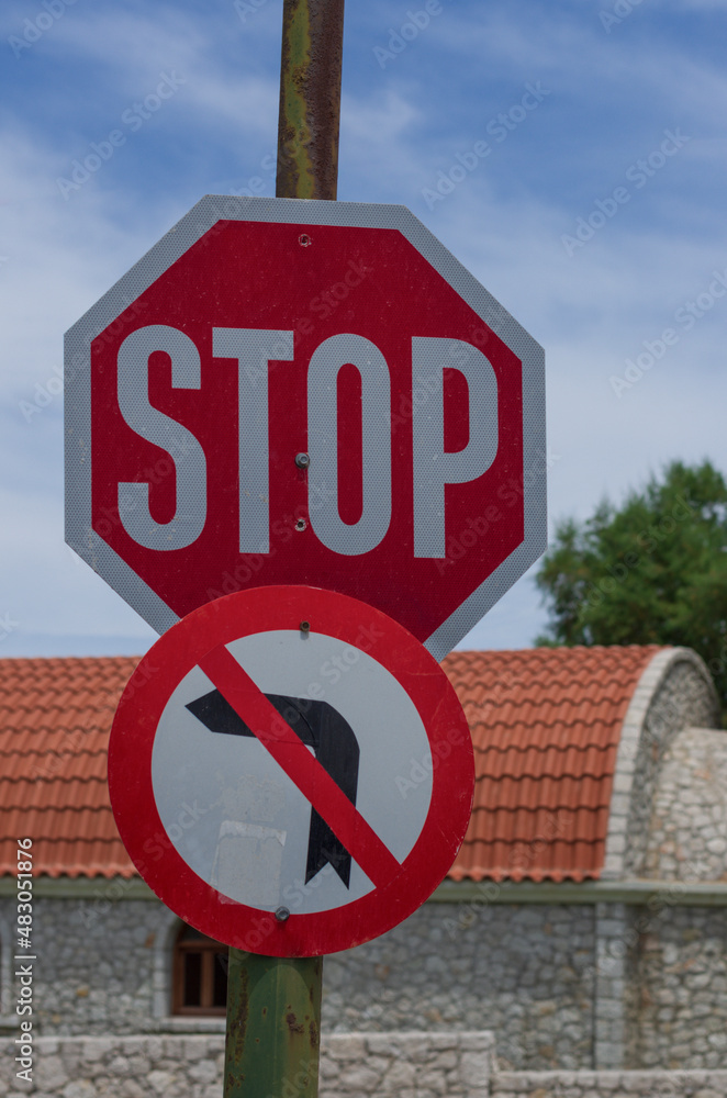 Road signs "Stop sign" and "No left turn" on an architectural blurred ...