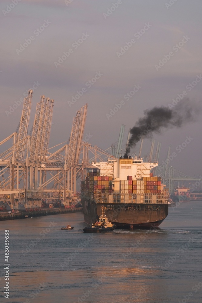 Harmful exhaust gases come out from the funnel of the container vessel ...