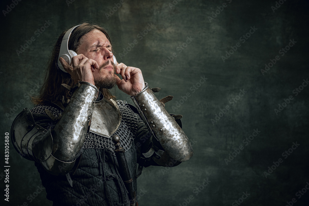 Young medieval warrior or knight with dirty wounded face in headphones ...
