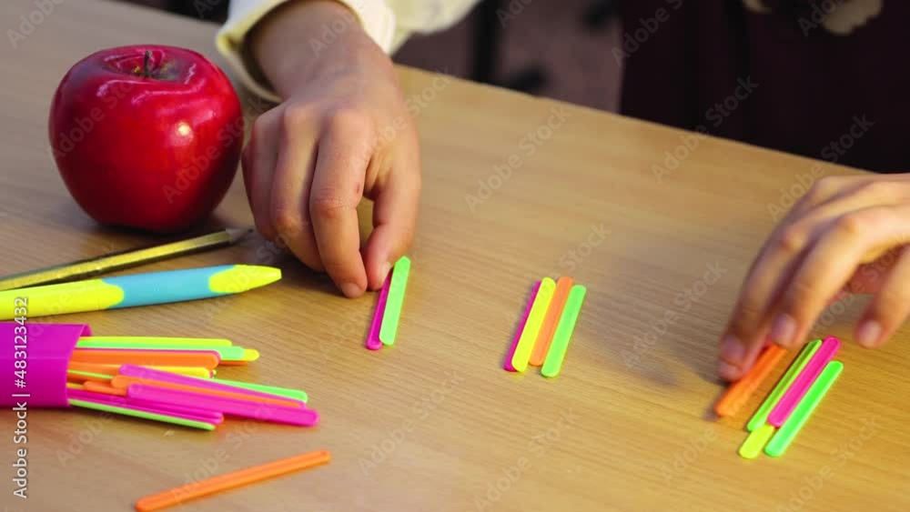 A student in the classroom or at home learns math with counting sticks ...