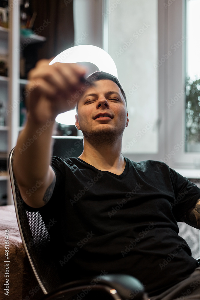 Creative artist man in a black T-shirt sits in a chair and points with ...