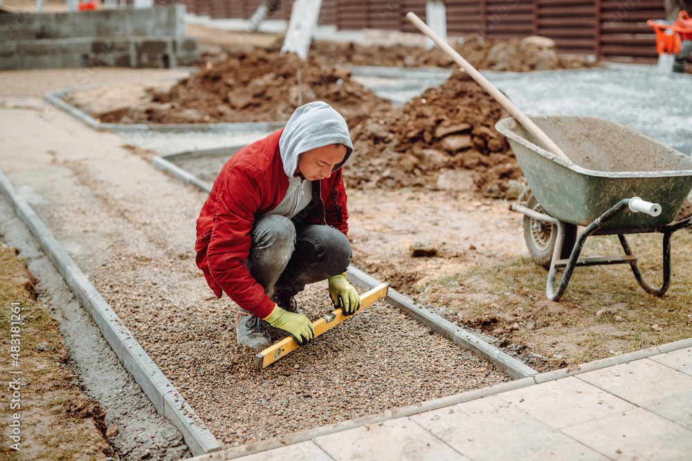 construction worker installing and laying pavement stones on terrace ...