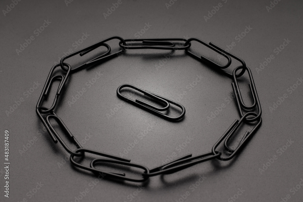 Black paper clip surrounded by a ring of linked black paper clips Stock ...