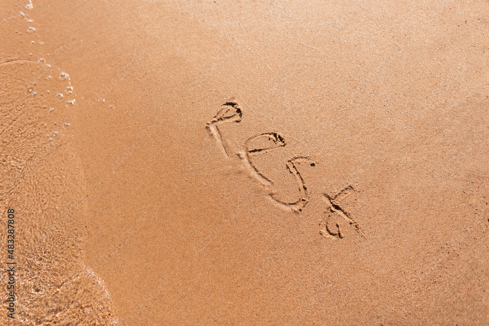The word Rest is written on the yellow sand on the beach with a wave ...