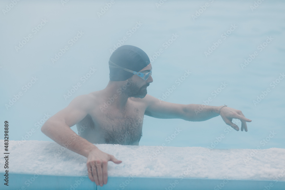 Fit swimmer male training swim in open winter swimming pool with fog ...
