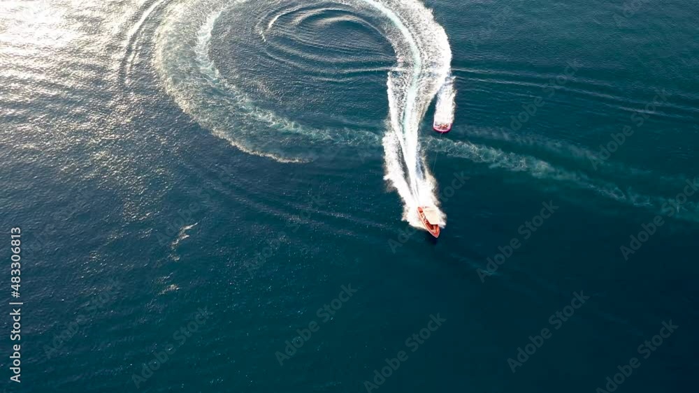 Video Stock Top down view of speed boat towing a big ski or wakeboard ...
