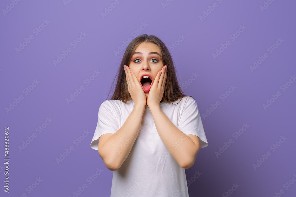 Shocked and concerned girl holding hands on face, open mouth and furrow ...