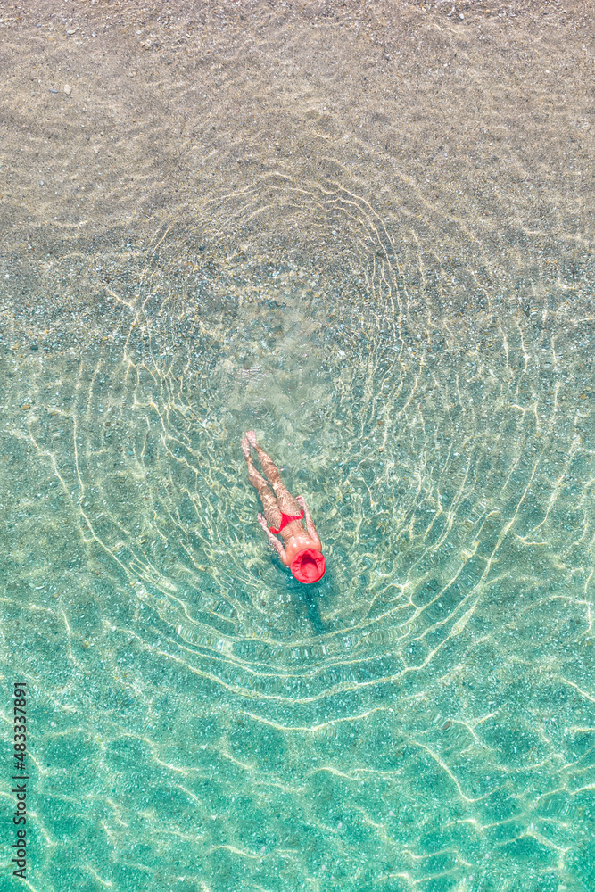 Top view. Young beautiful woman in a red hat and bikini swimming in sea ...